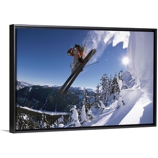 "Male skier jumping off snow cornice, holding skis, low angle view ...