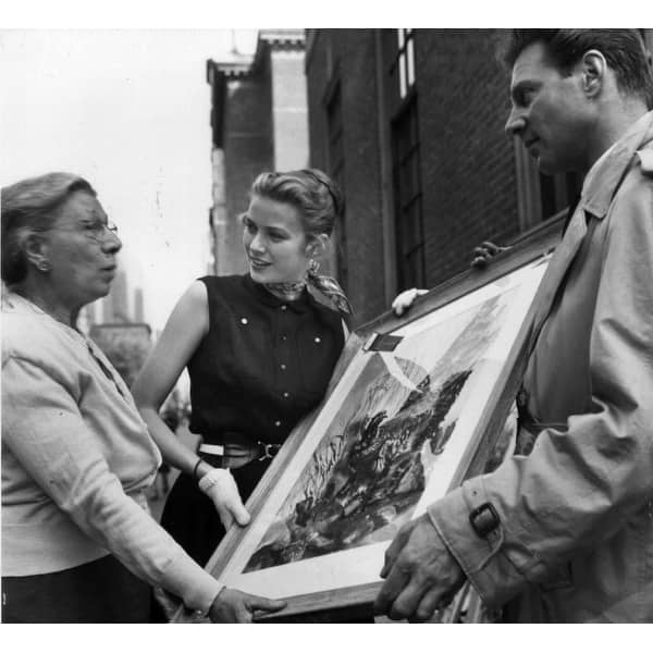 Grace Kelly and Jean Pierre Aumont give a painting to an old woman ...